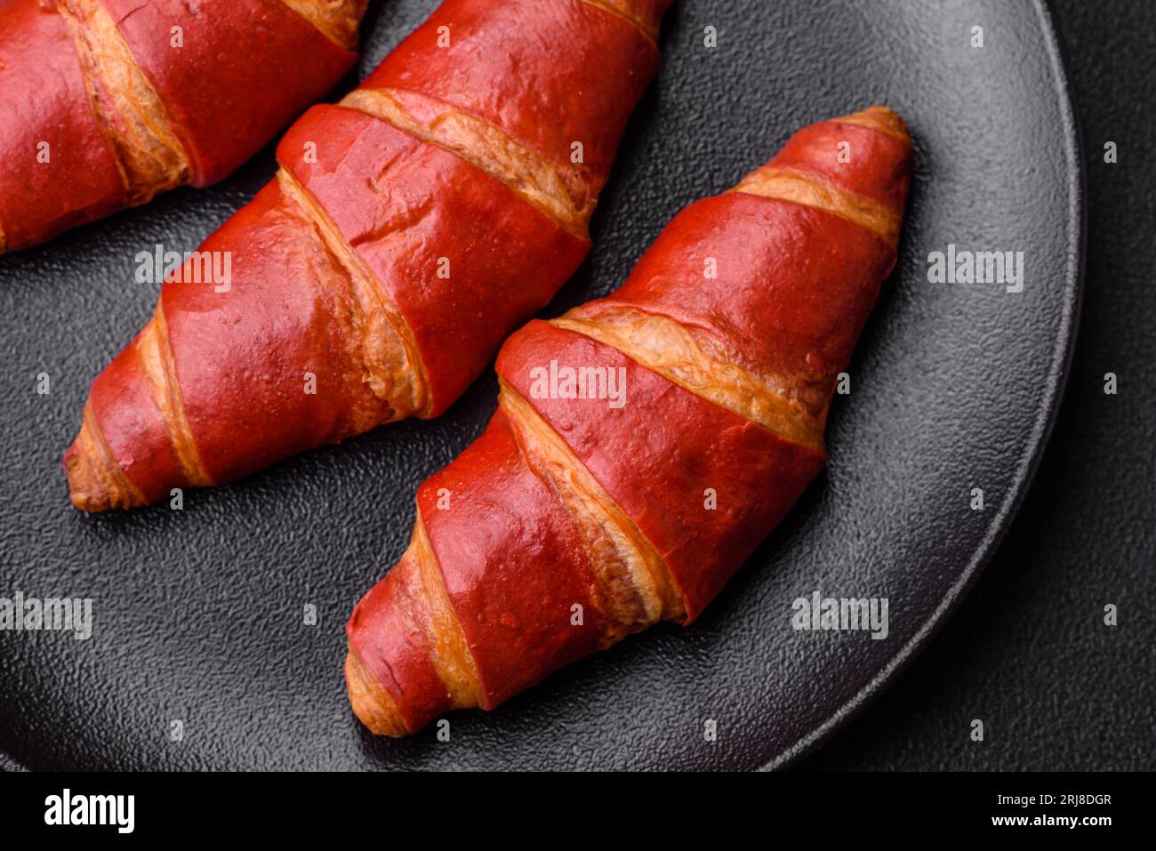 Delicious sweet crunchy red croissant with cream filling on dark ...