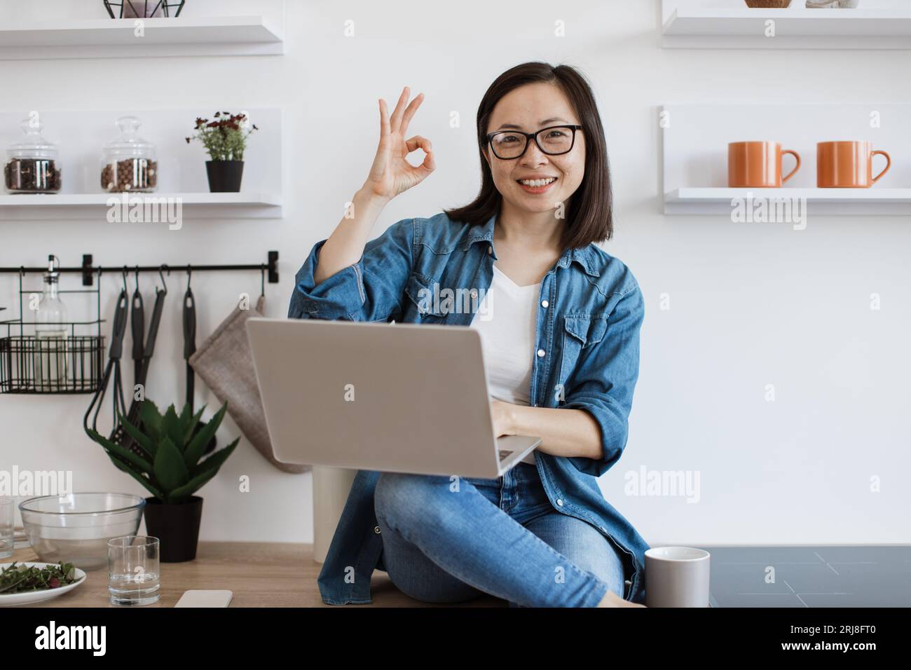 Female freelancer using computer on kitchen work surface Stock Photo ...