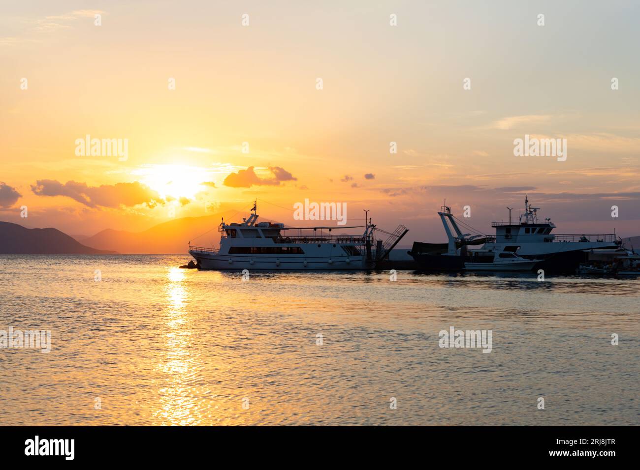 Ships and boats in the harbour at sunset at the island of Evia in ...