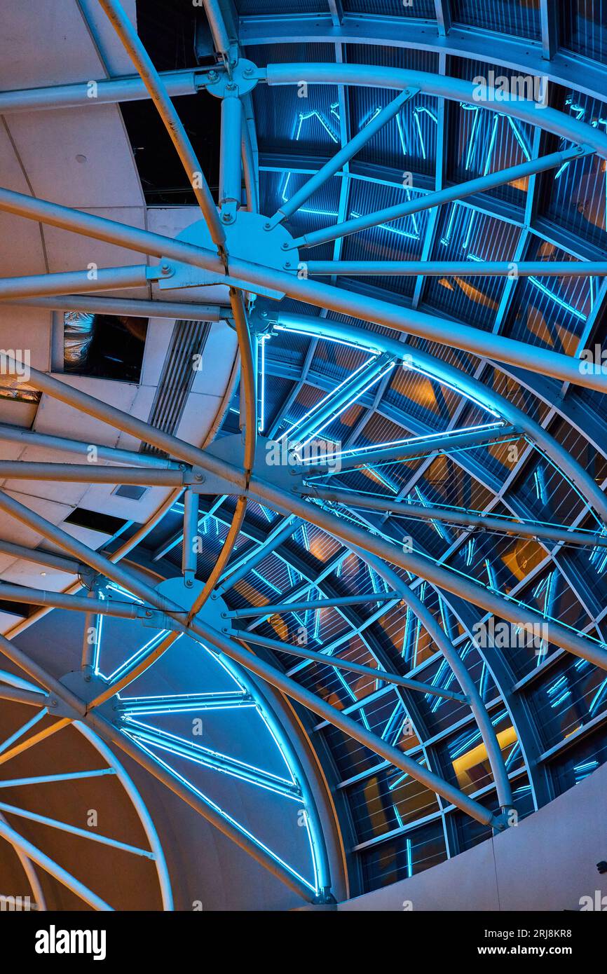 Neon blue lights illuminating multiple white metal beams on curved ...