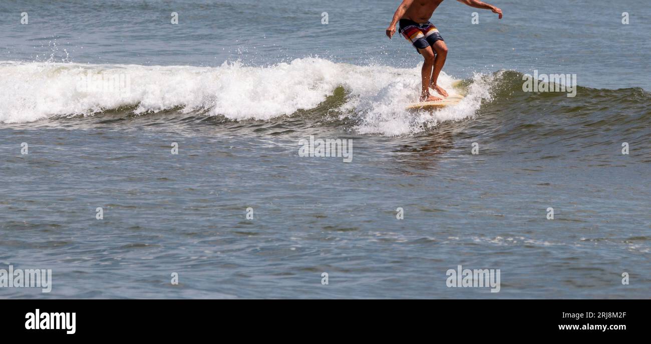 Front view of a surfer riding a wave at Gilgo Beach in July of 2023 ...