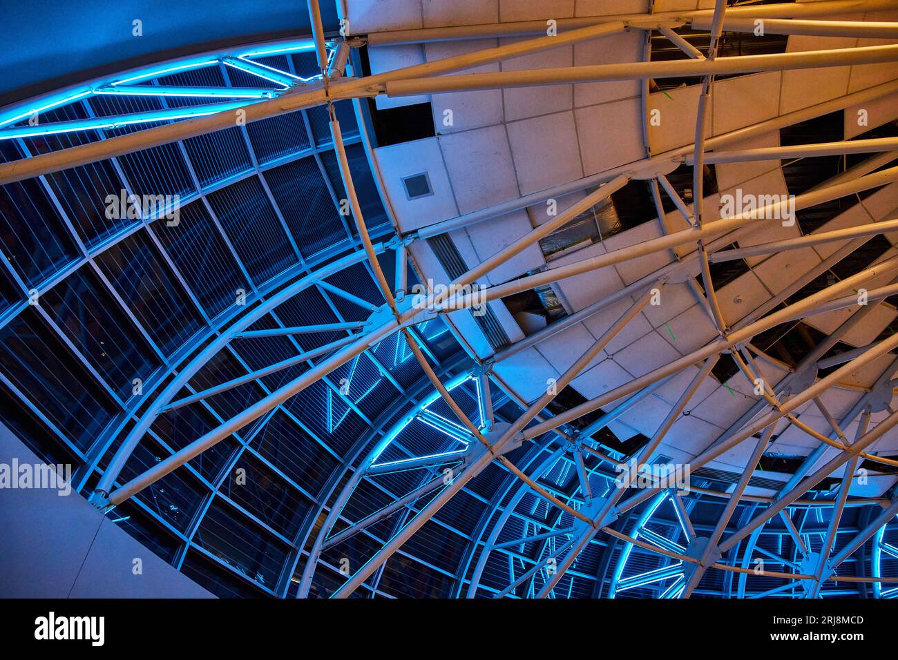 Curved windows supported by white beams illuminated by neon blue lights ...