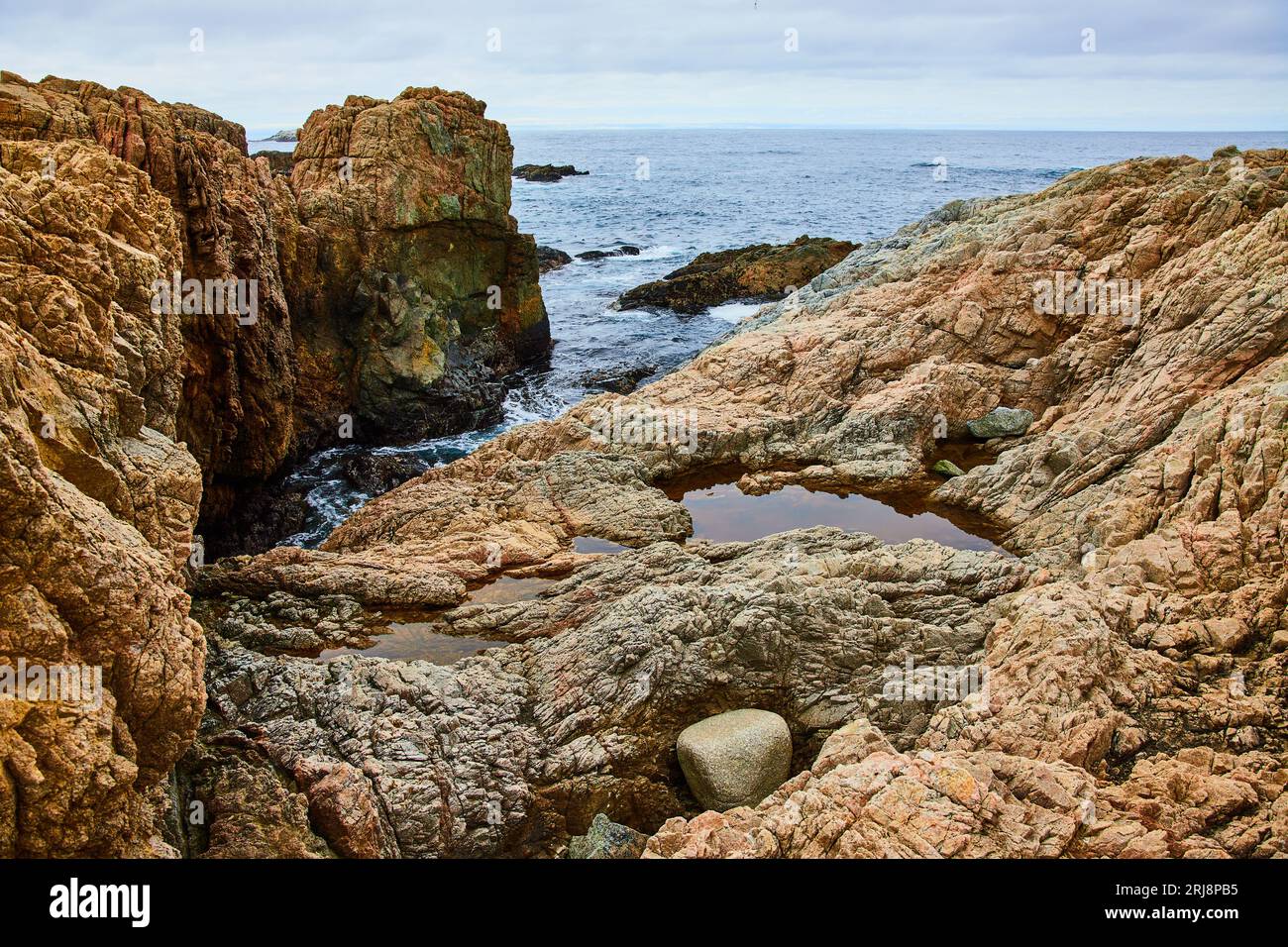 Rough cliff face crags with tide pools and Pacific Ocean flowing ...