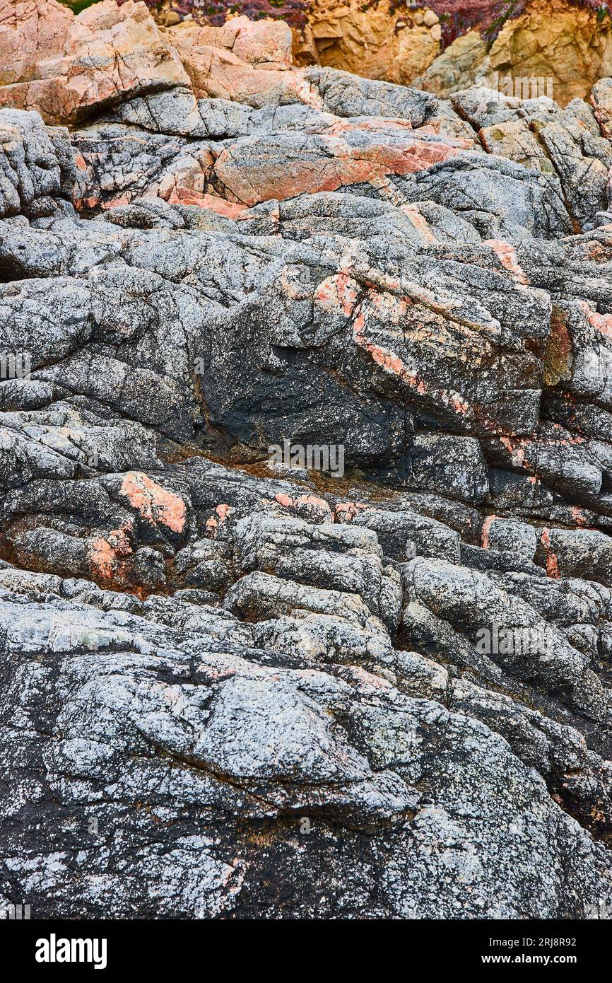 Light and dark gray stony cliff wall with tan rock and cracks in stone ...