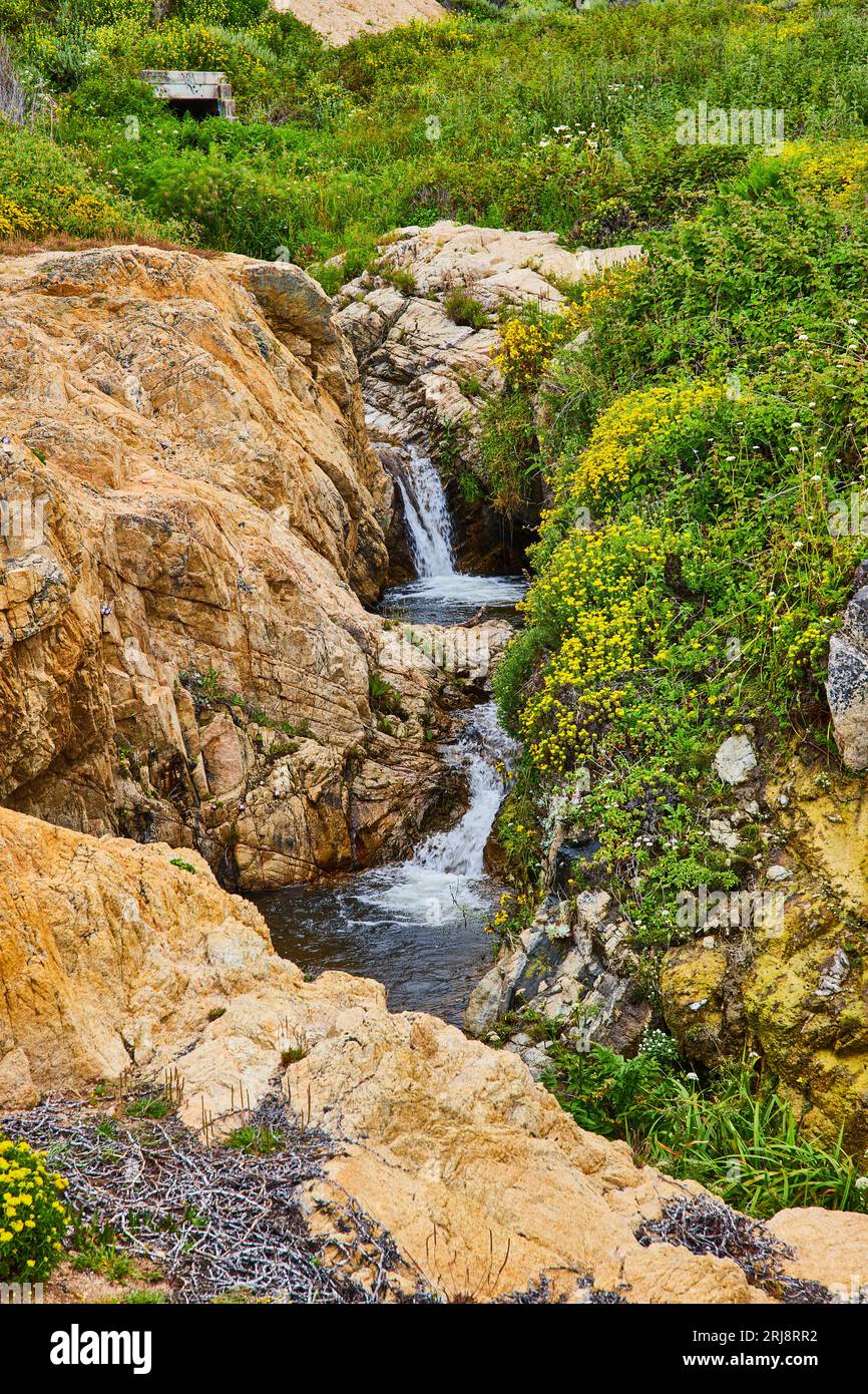 Scenic creak and two waterfalls cutting between cliff rock with yellow ...