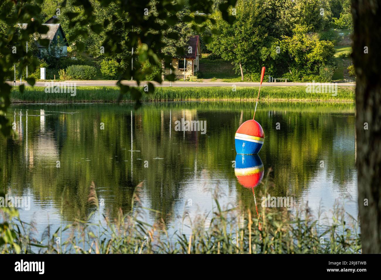 Enormously big funny colourful fishing float in the calm mirror water lake Stock Photo - Alamy