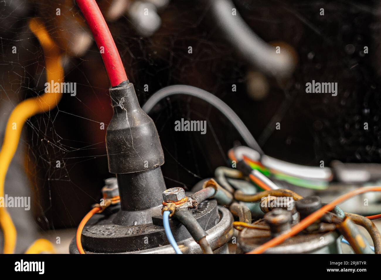 Old rusty spider web covered combustion motor ignition coil with wires ...