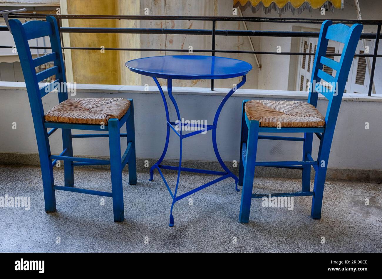 A white balcony with two bright blue chairs and a small table Stock ...