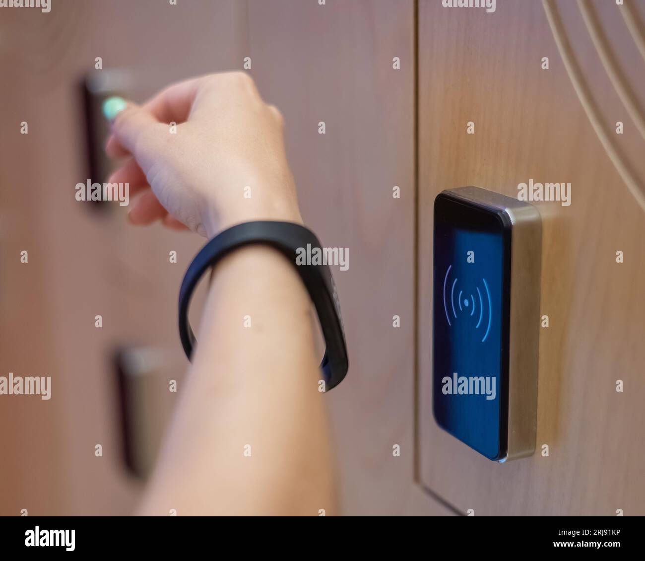 A woman opens the electronic lock of a cubicle in a locker room with a ...