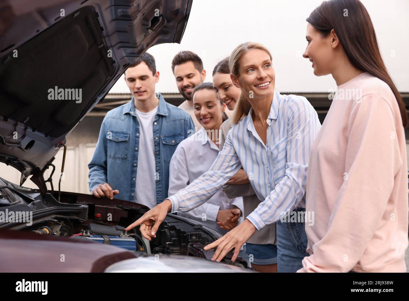 Driving school. Teacher explaining car engine to group outdoors Stock ...