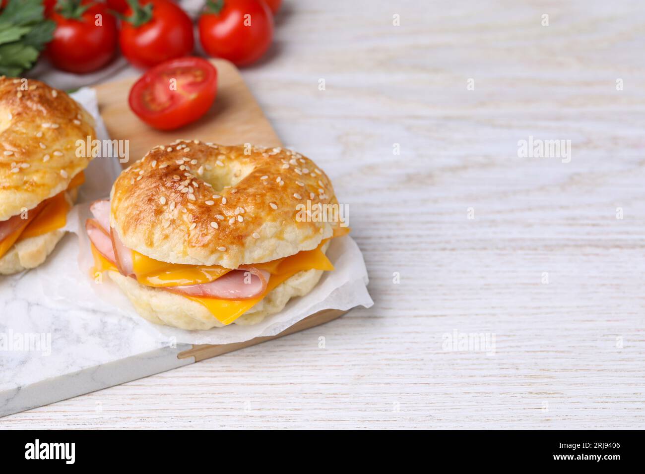 Delicious bagels with ham, cheese and products on white wooden table ...