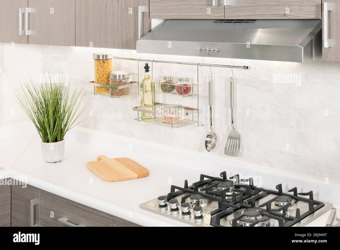 A modern kitchen with white countertops and grey cabinets featuring a ...
