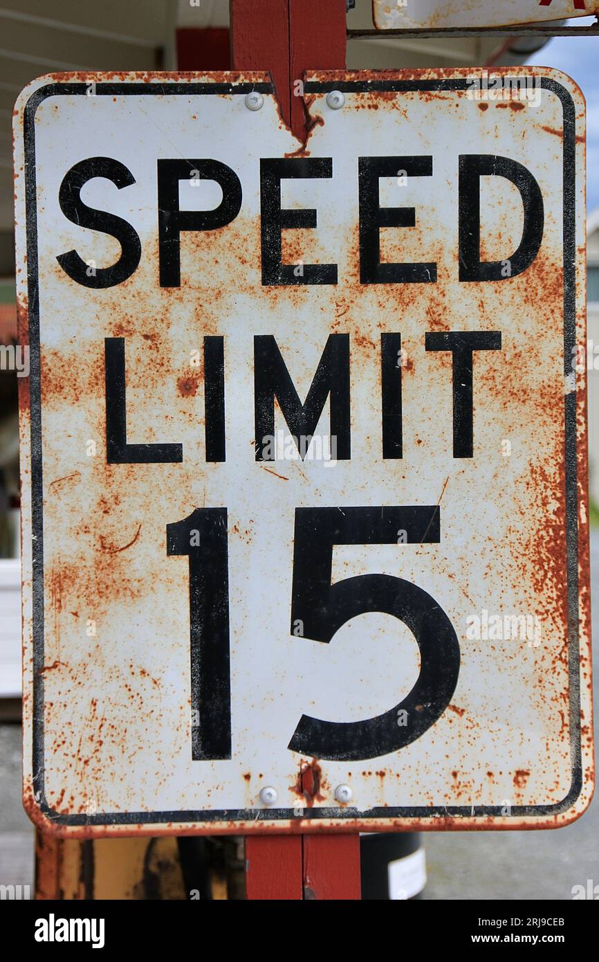 A rusted metal speed limit sign affixed to a tall metal pole in a rural ...