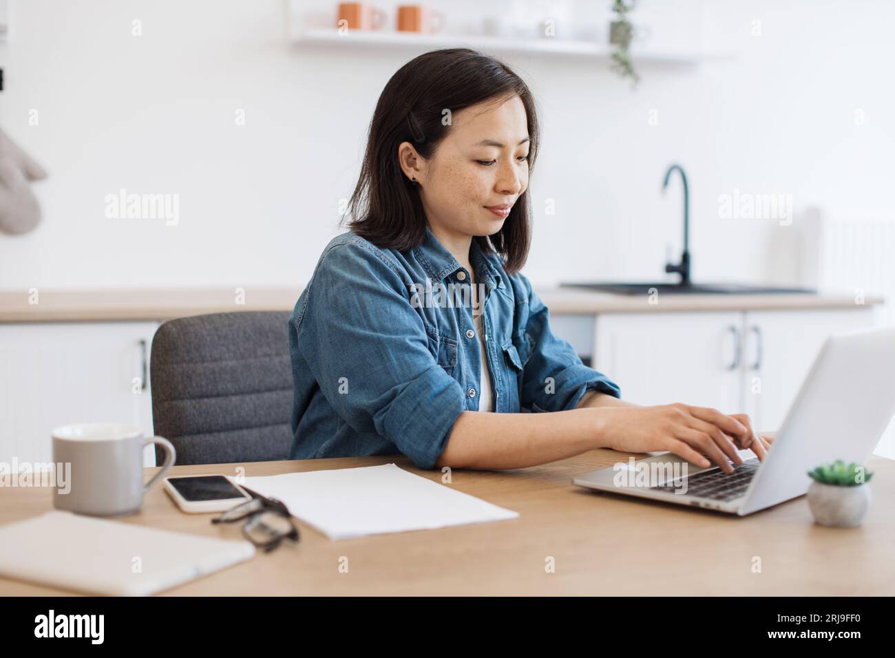 Female adult using portable device in kitchen interior Stock Photo - Alamy