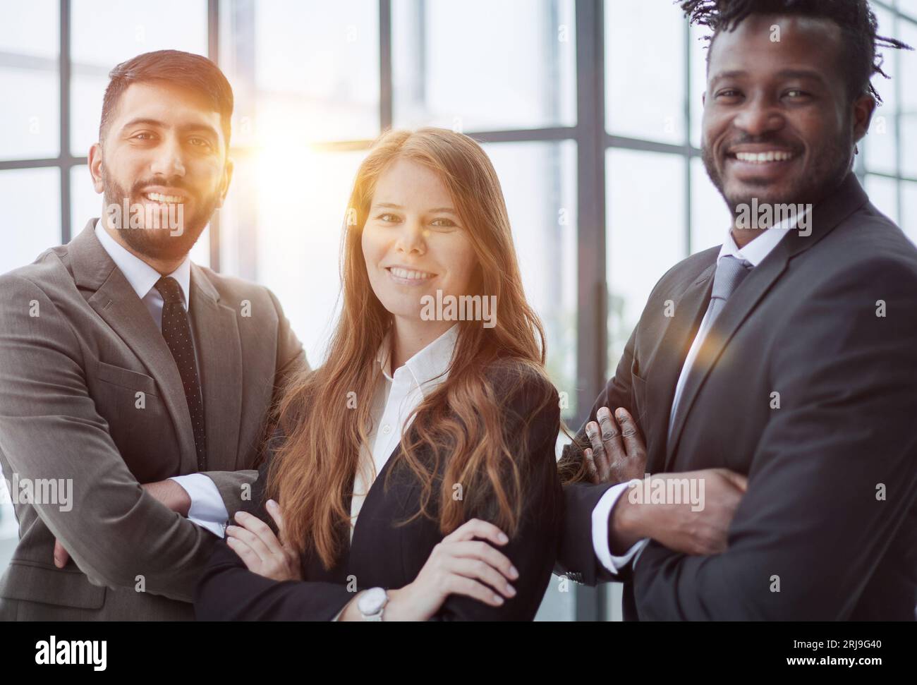 Three professionals in formal suits standing for camera indoors and ...