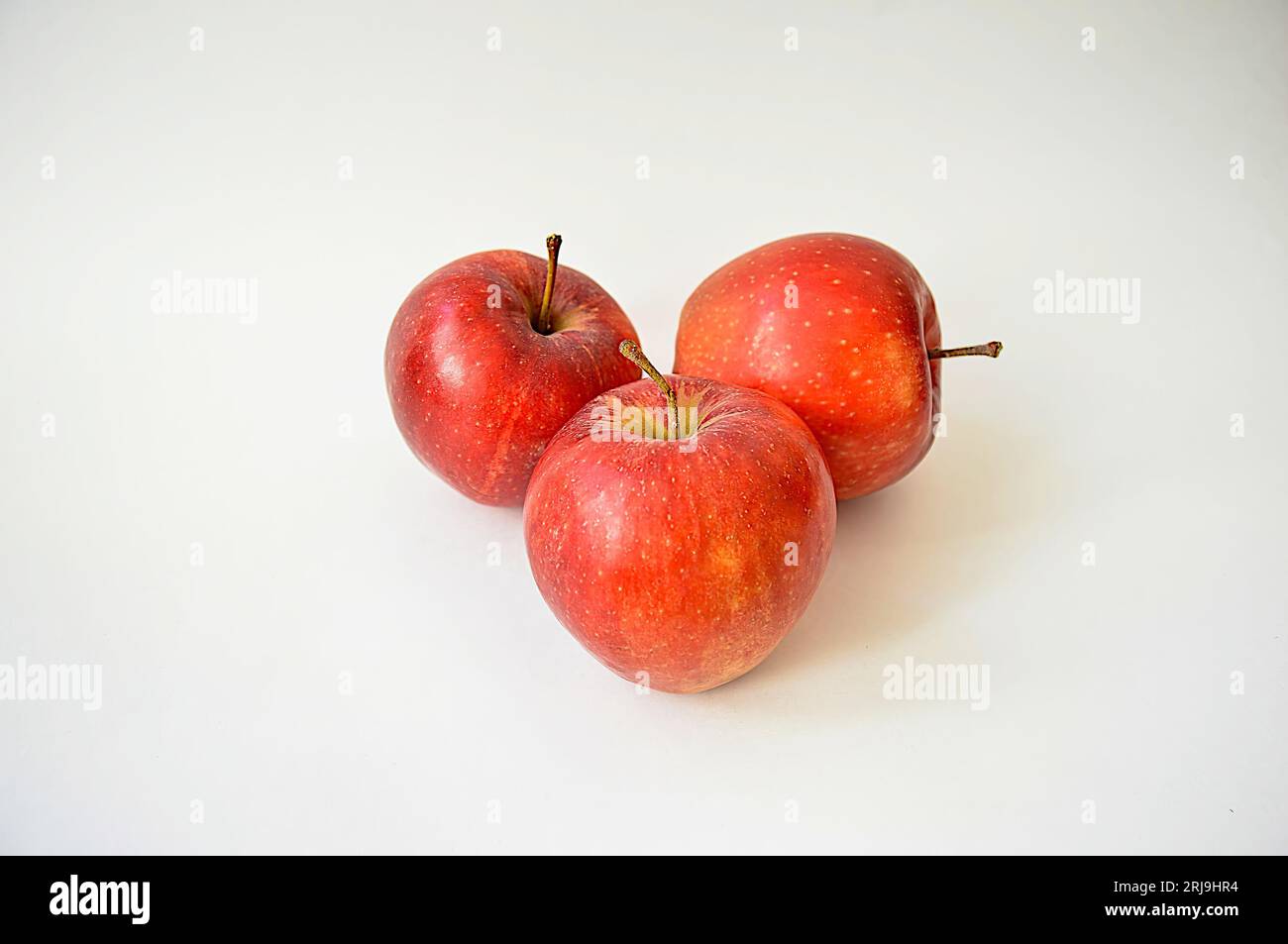 One big appetizing red apple in front of two red apples isolated on ...