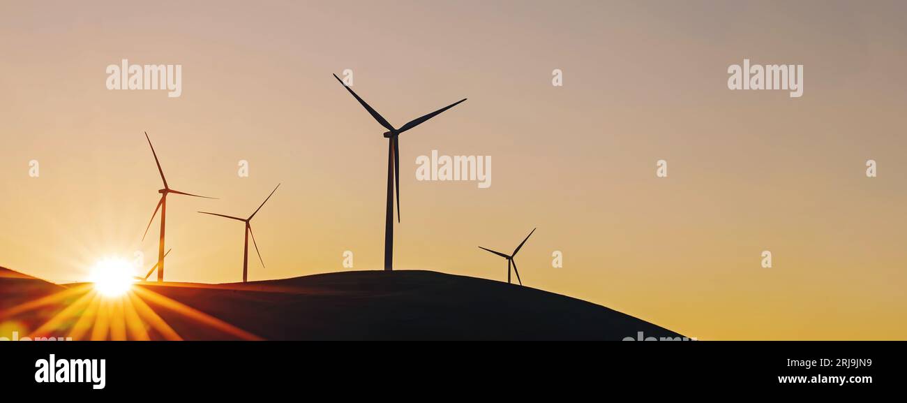 Banner with wind turbines on the hills in back light of rising sun ...