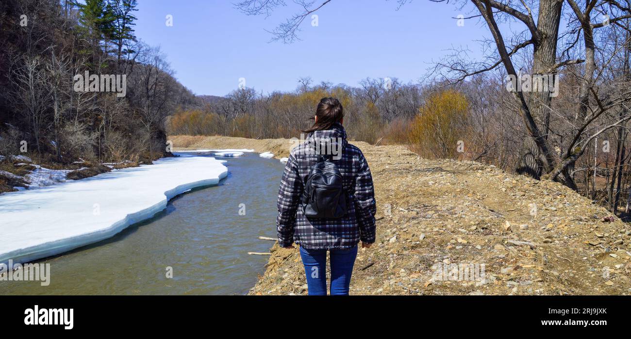 Young brunette woman going camping in the forest next to a melting ...