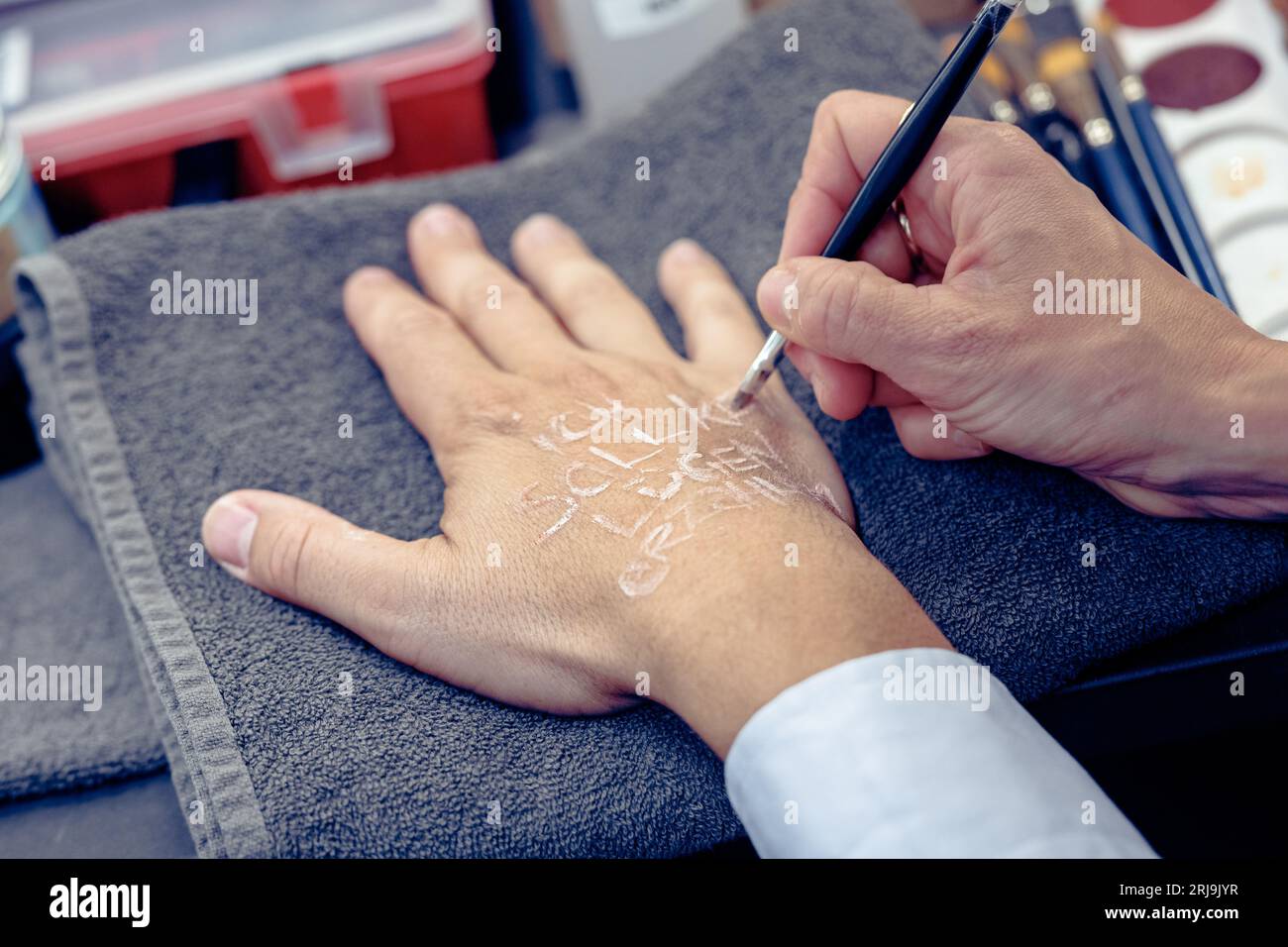 Hamburg, Germany. 17th Aug, 2023. A makeup artist applies a text scar ...