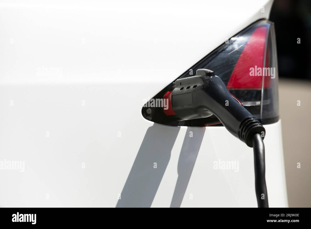 Detail view of an electric vehicle (EV) charging via plug in cable ...