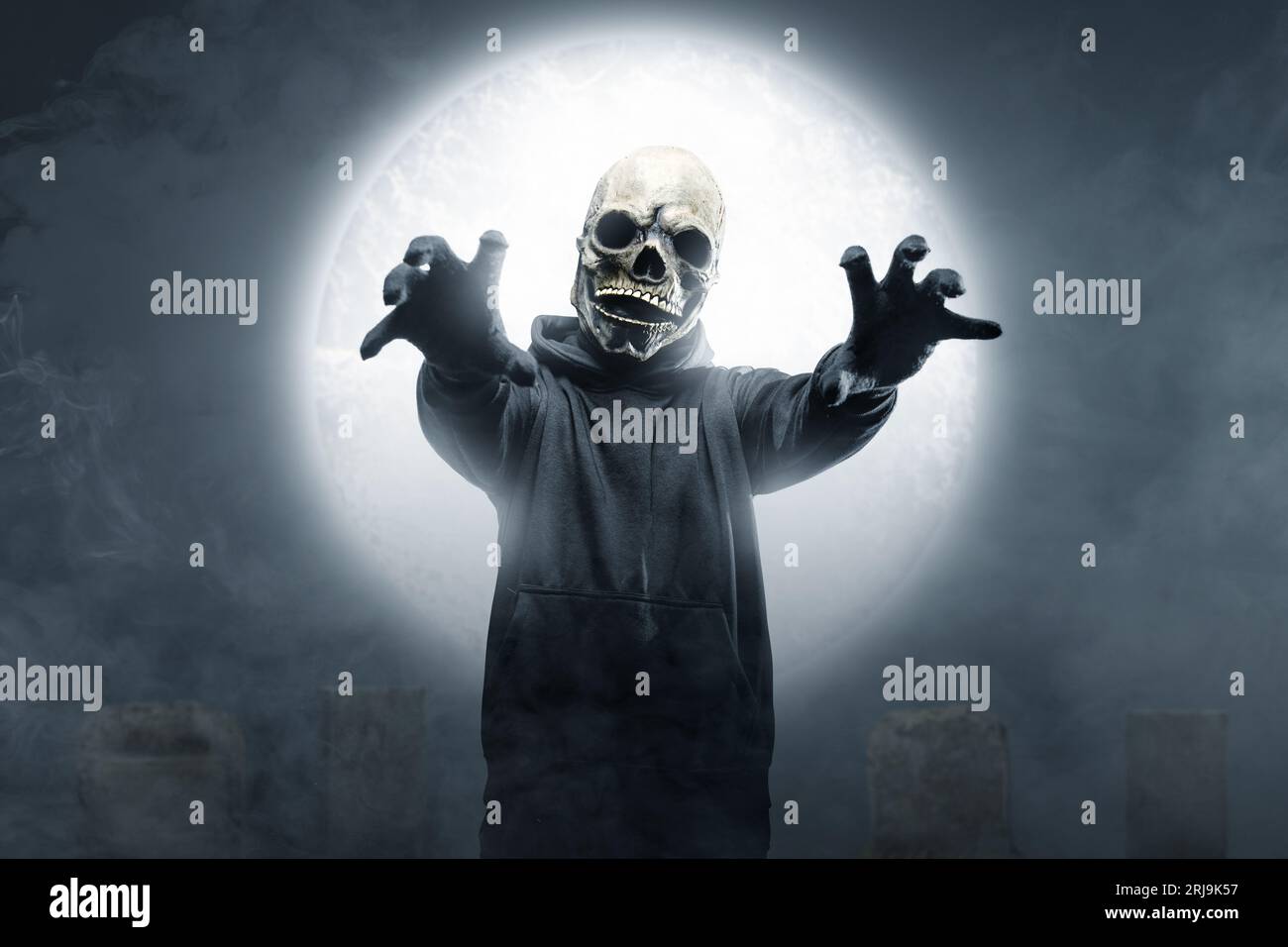 A man with a skull head is standing in the graveyard with a night scene ...