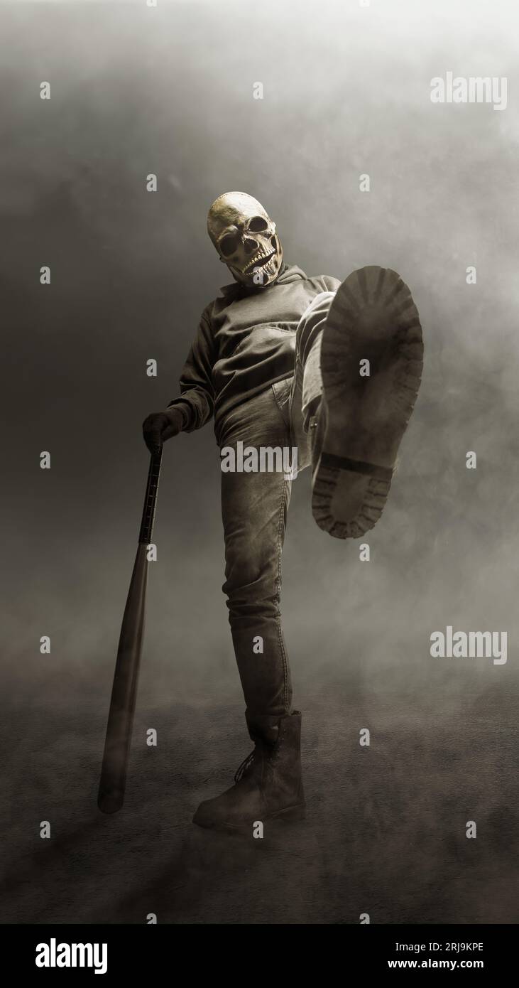 A man with a skull head is standing with a baseball bat in the dark ...