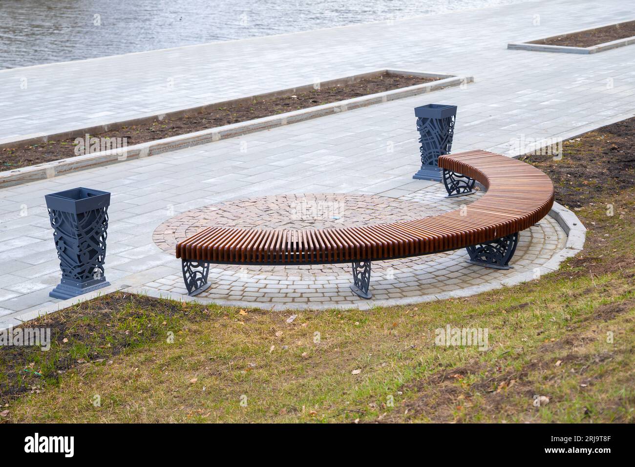 long outdoor wooden arch shaped bench on embankment of city river ...