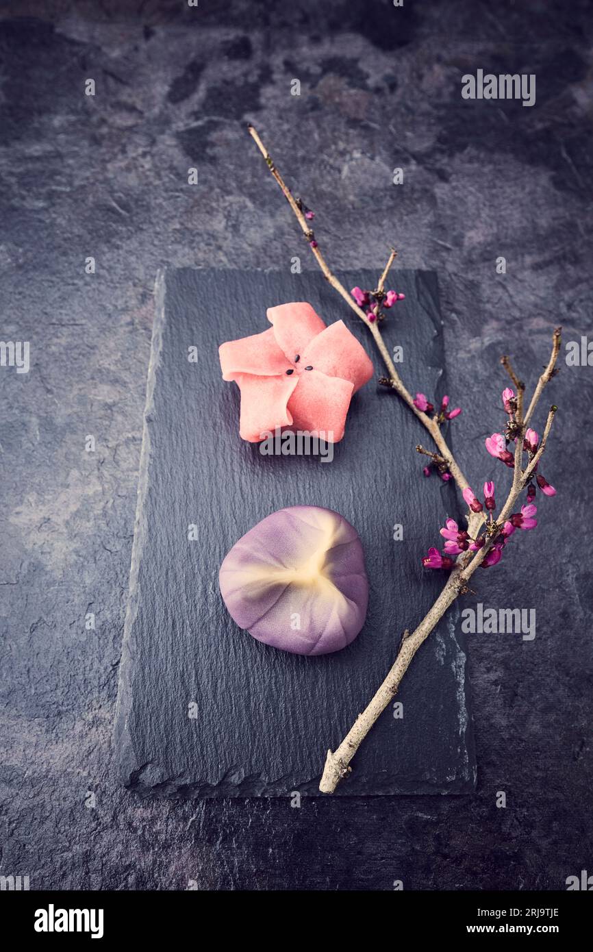 Two Japanese sweets and branches on a black stone slab Stock Photo - Alamy