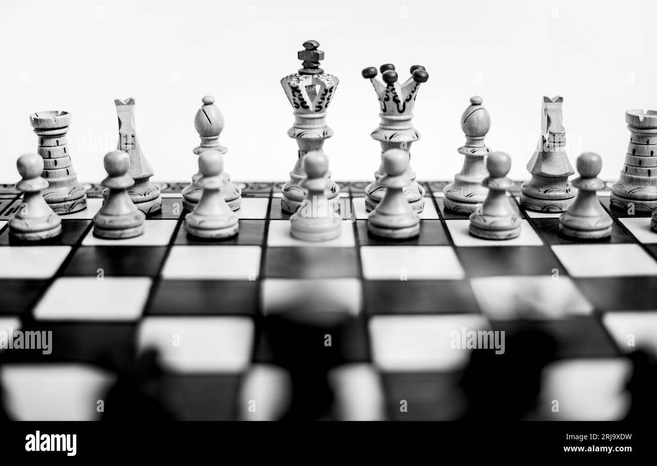 A grayscale shot of a chessboard with a full set of chess pieces ...