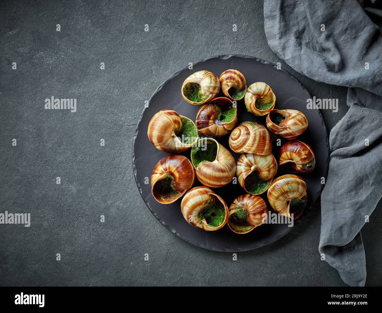 plate of baked escargot snails filled with parsley and garlic butter on ...