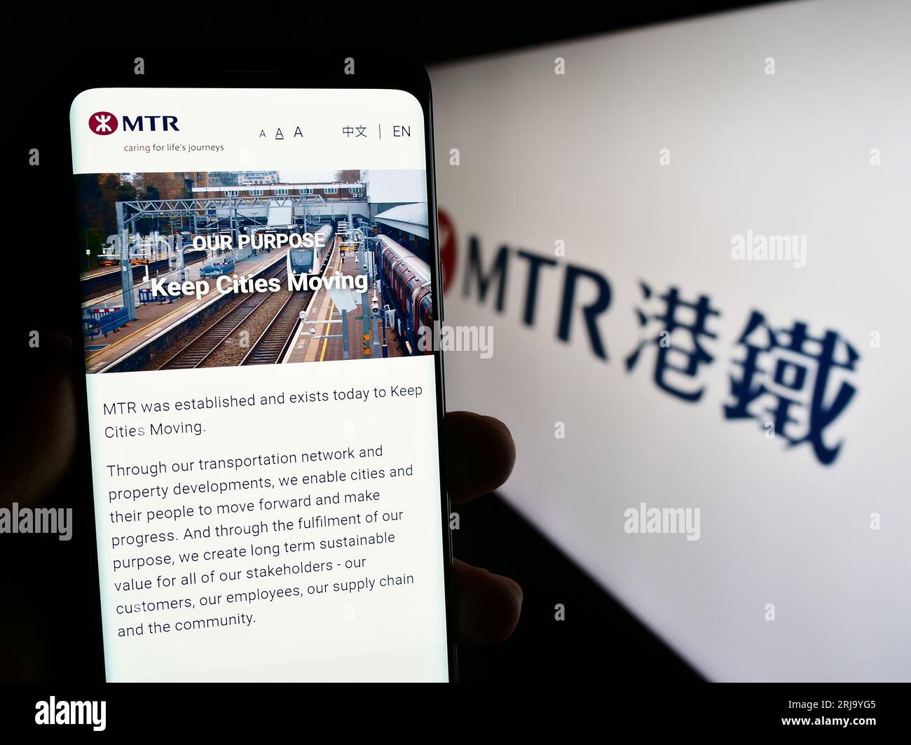 Person holding mobile phone with web page of Chinese rail company MTR ...