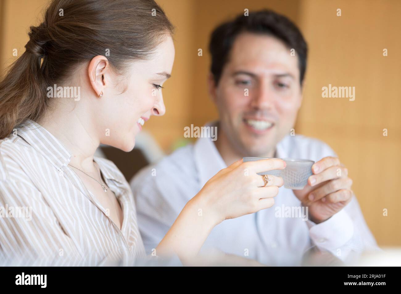 Foreign man and woman toasting with sake Stock Photo - Alamy