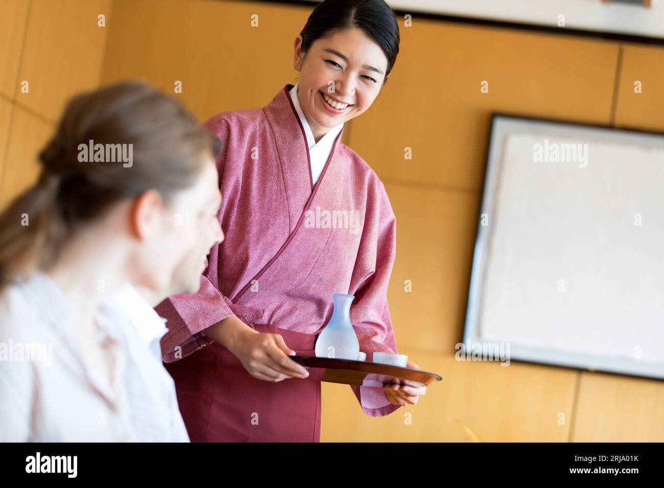 Female shop assistant serving sake to a foreigner Stock Photo - Alamy