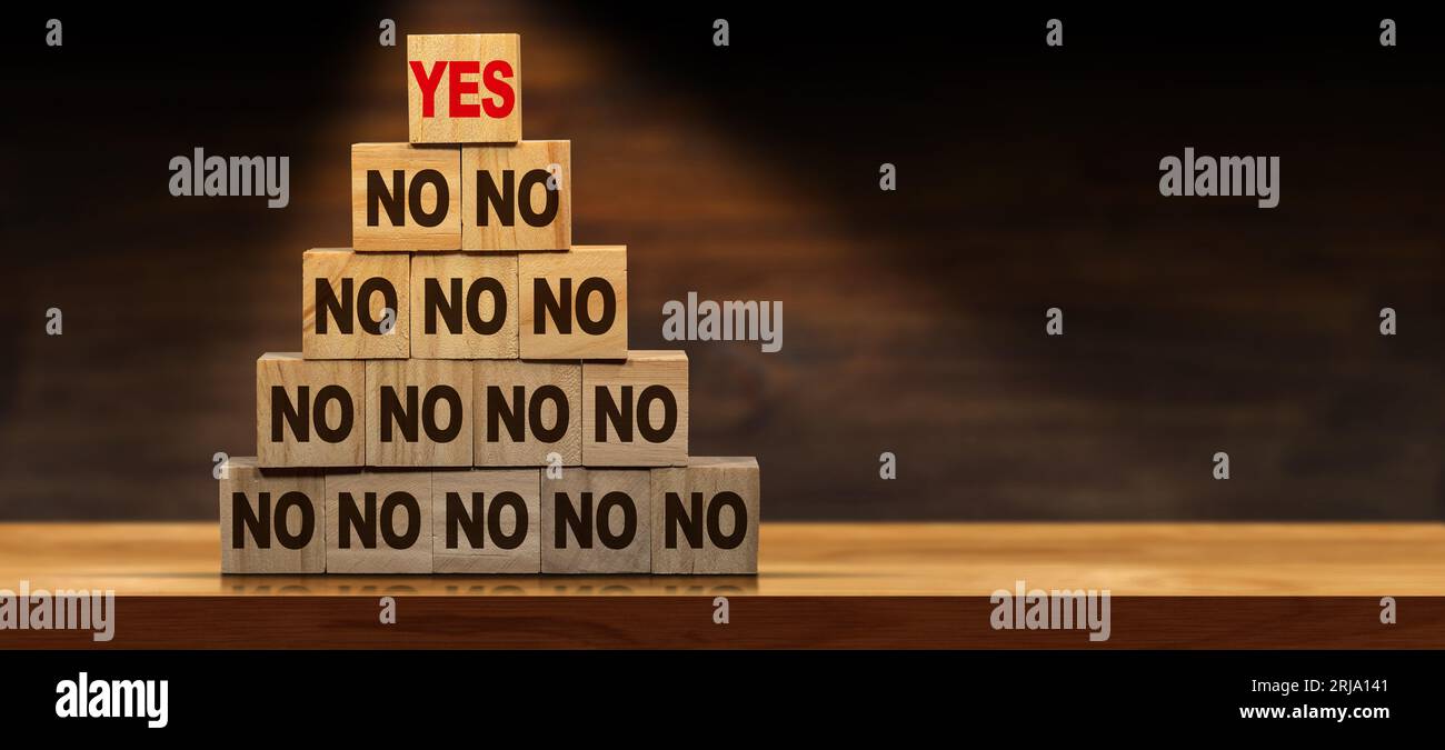 Stack of wooden blocks with text Yes or No. Above a wooden table or desk with copy space Stock ...