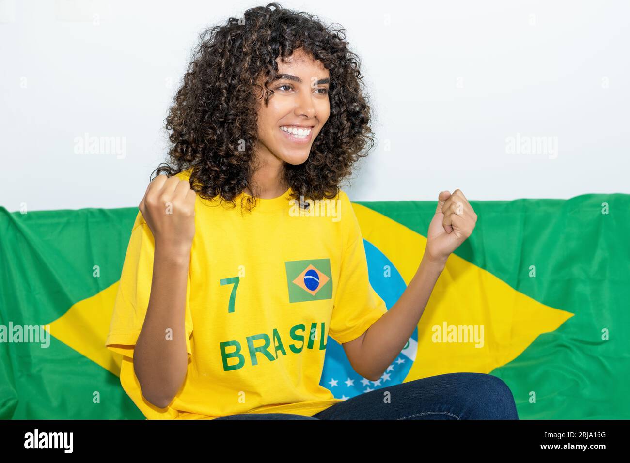 Cheering brazilian female soccer fan with flag of Brazil watching game ...