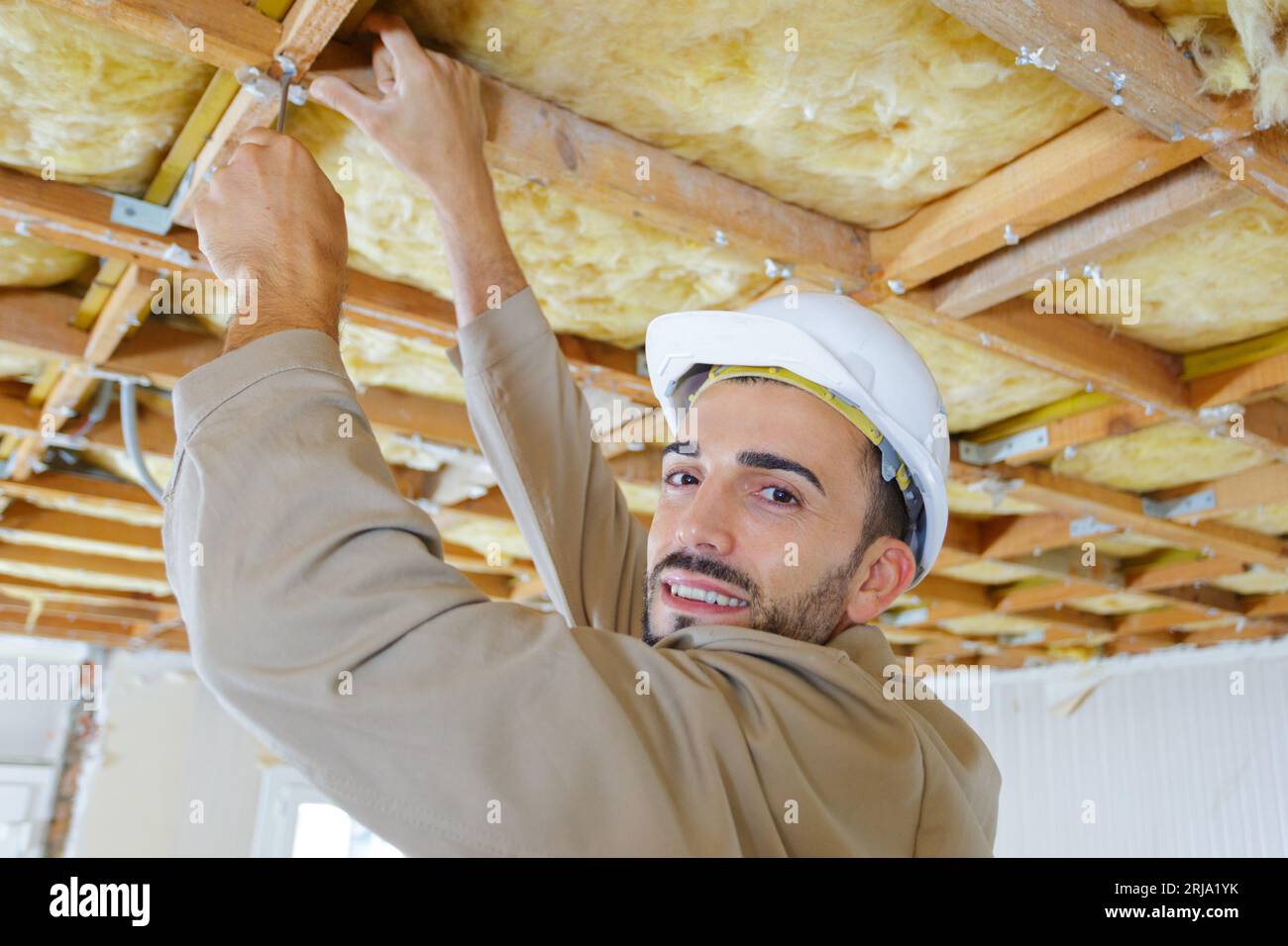 builder drives screws into ceiling of fiberboard with a screwdriver ...