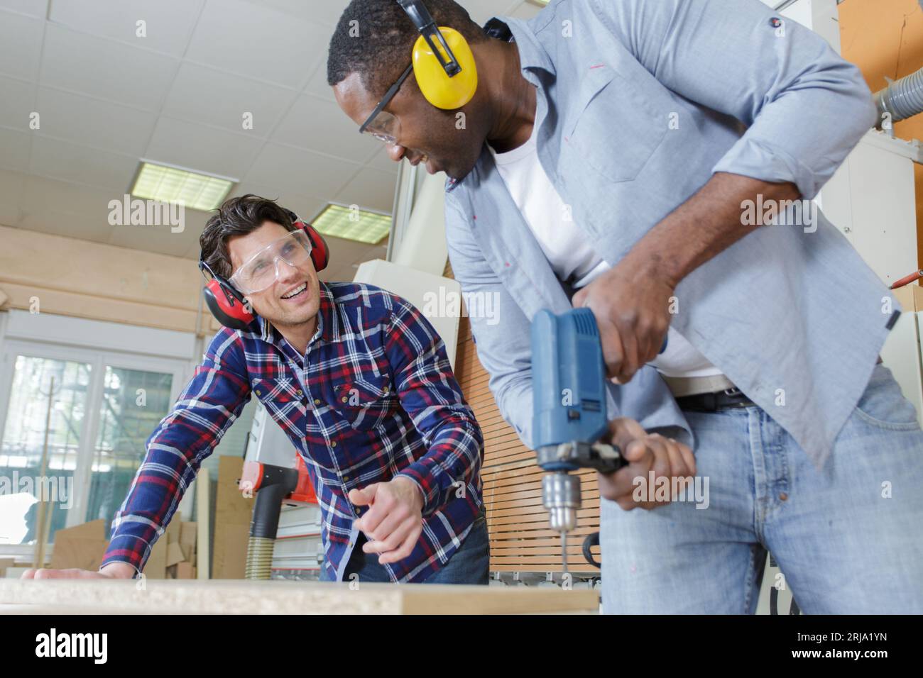 builder with apprentice at work using electric drill Stock Photo - Alamy