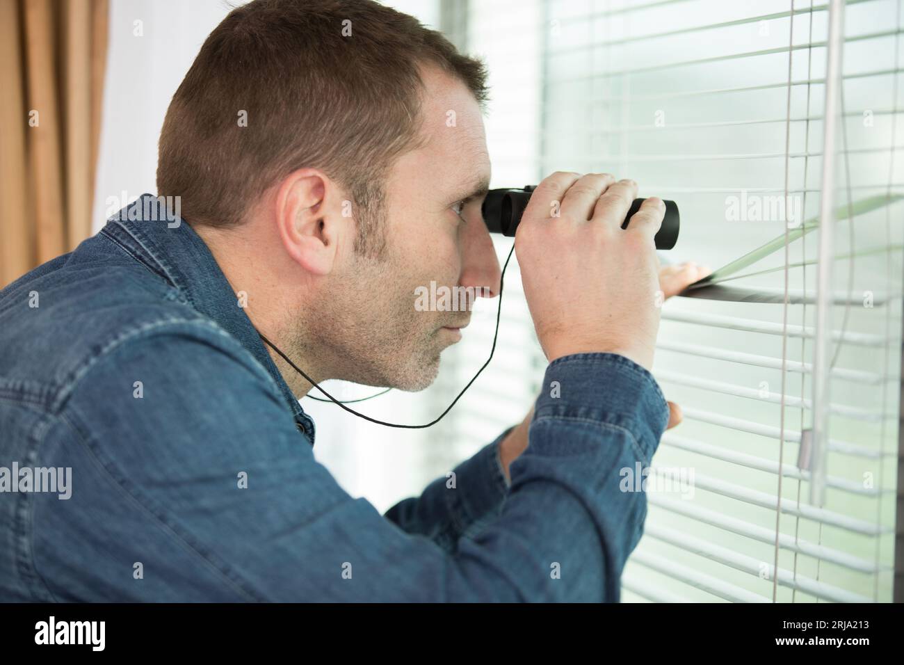 man looking through window with binoculars Stock Photo - Alamy