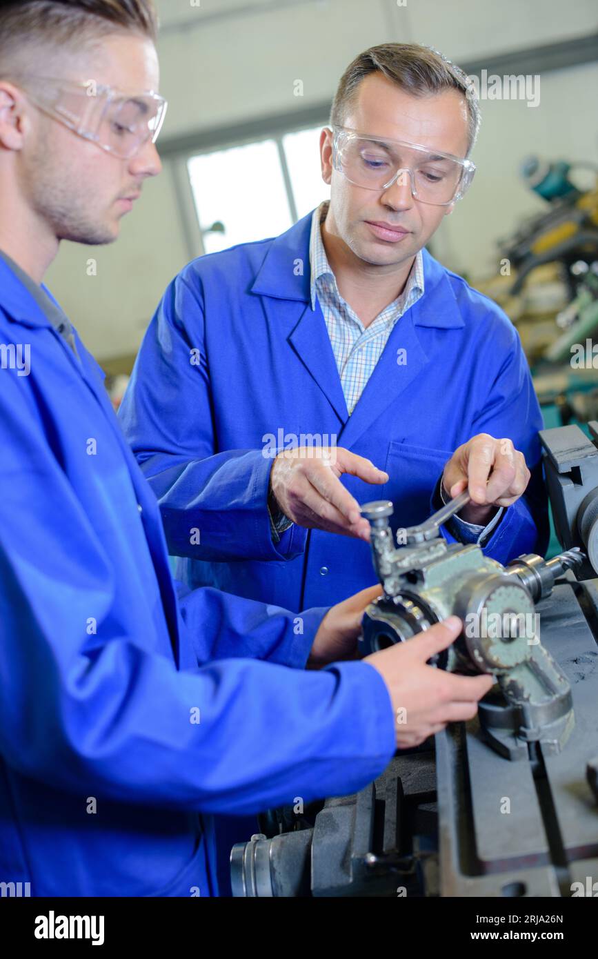 Engineer and apprentice holding mechanical part Stock Photo - Alamy
