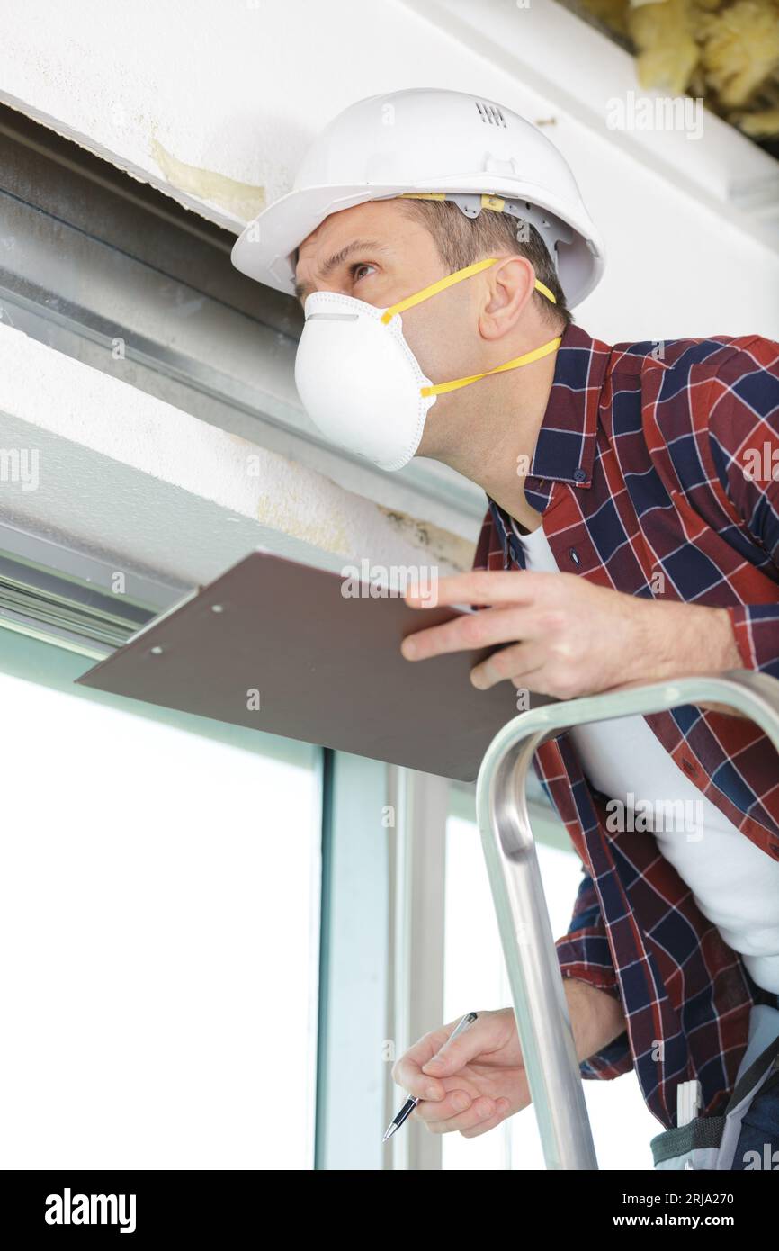 male builder wearing a mask securing window frame Stock Photo - Alamy