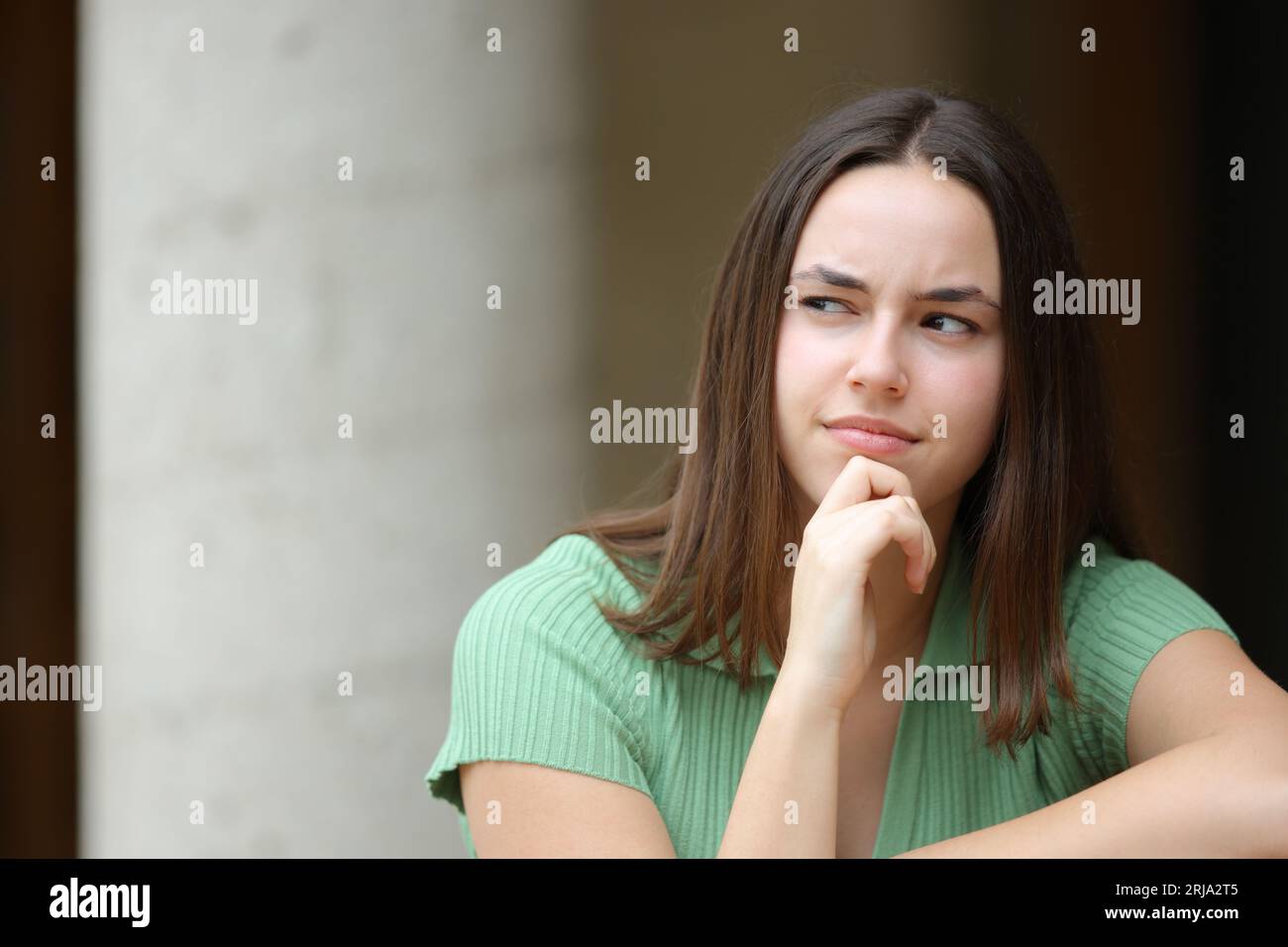 Front view portrait of a pensive woman in the street looks at side ...