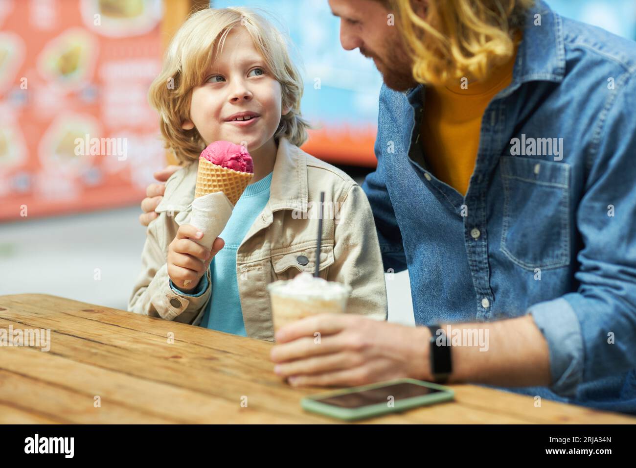 Portrait of father and son eating ice cream and enjoying bonding time ...