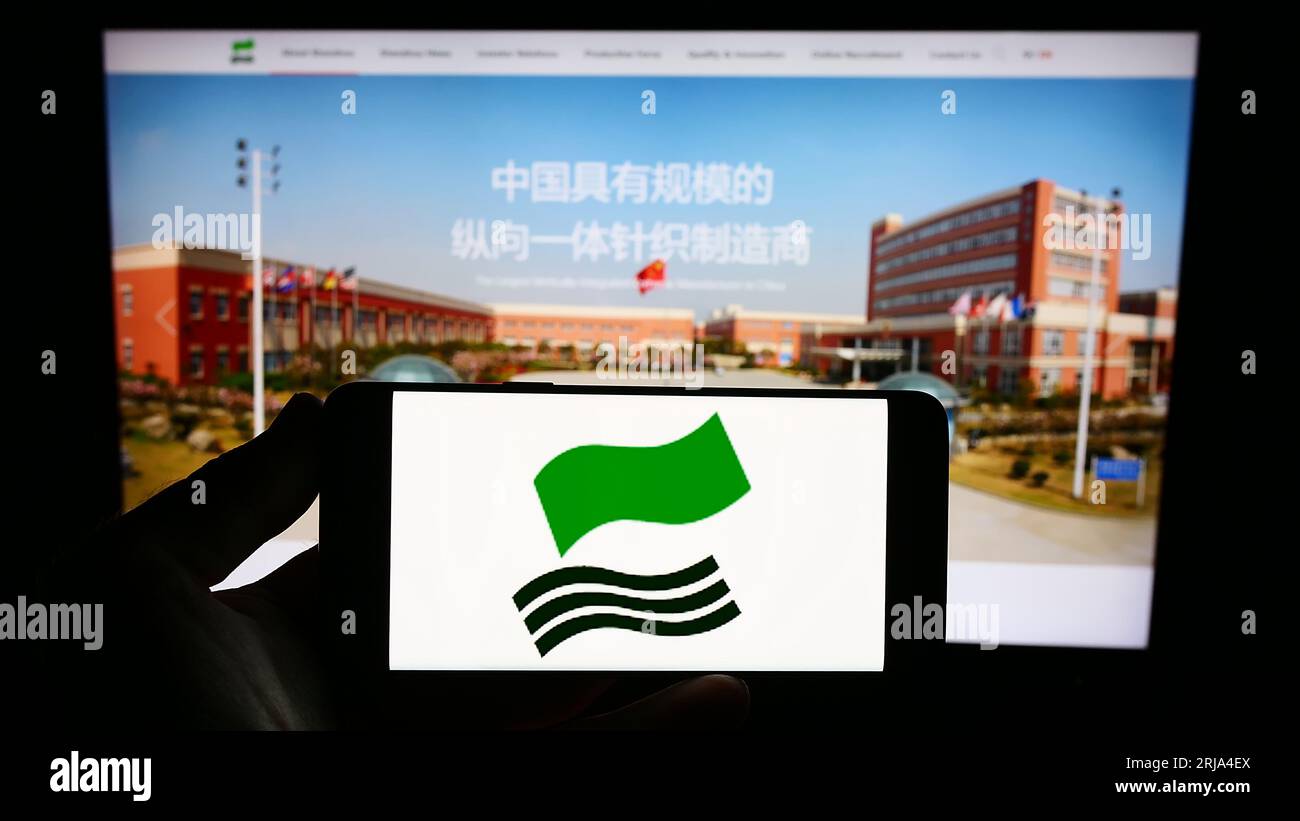 Person holding smartphone with logo of Shenzhou International Group ...