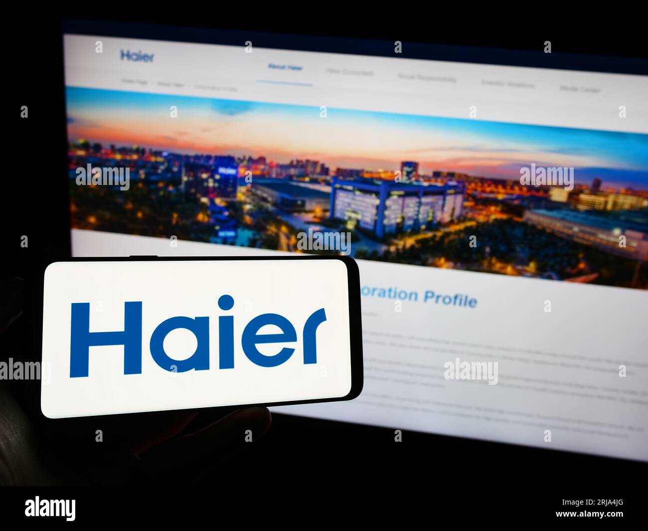 Person holding mobile phone with logo of home appliances company Haier ...