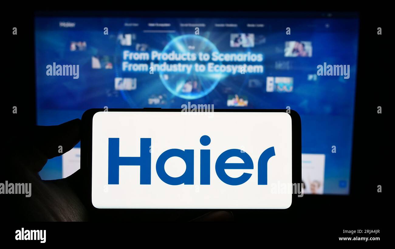 Person holding cellphone with logo of home appliances company Haier ...