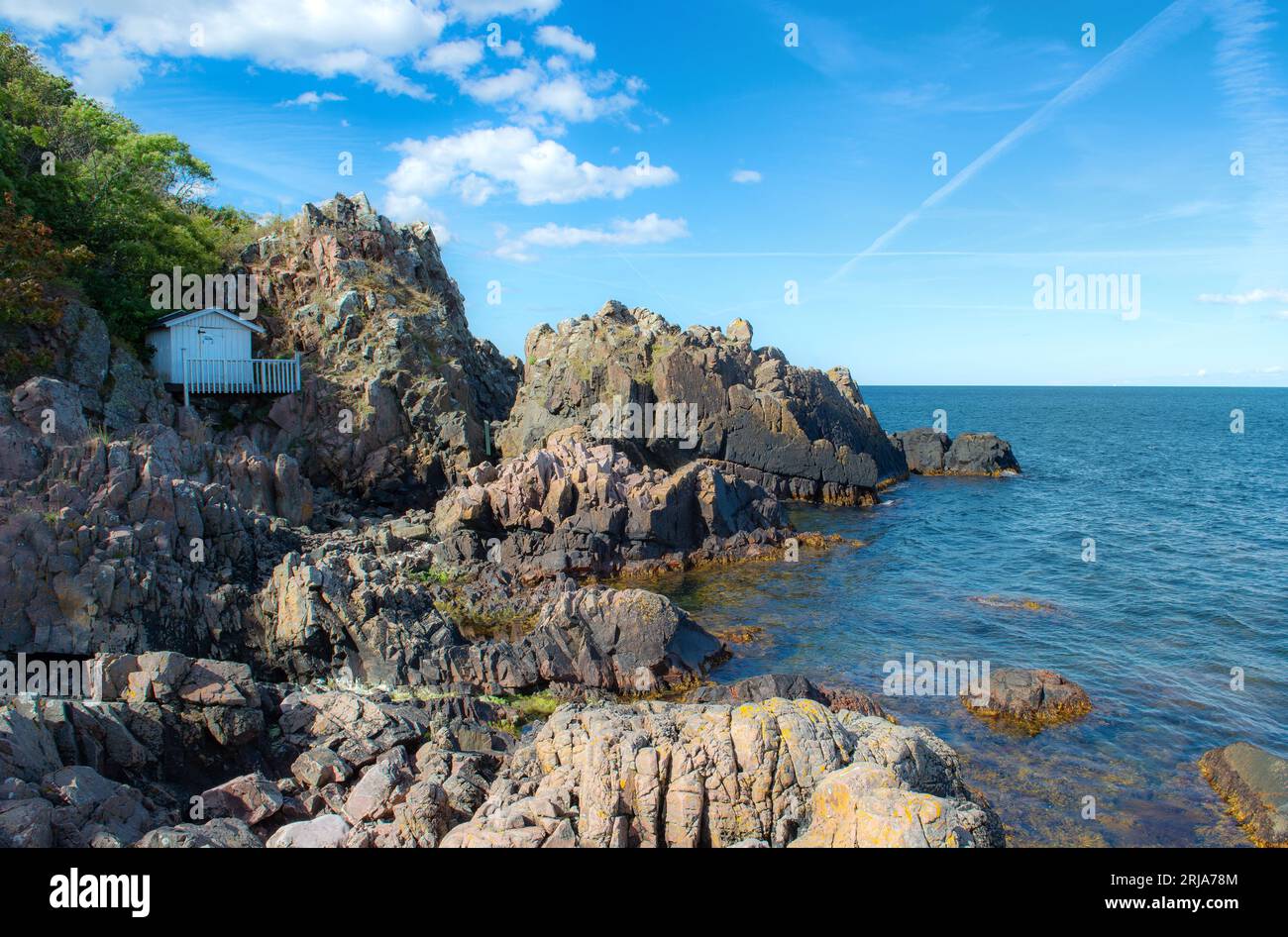 little white cabine in the cliff at the edge of the sea in sweden under ...