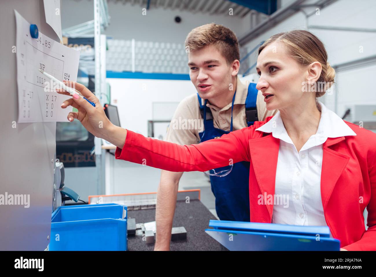 Worker and manager on factory floor discussing product specifications ...