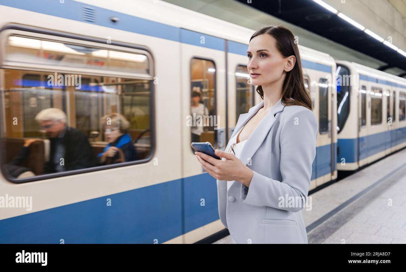 woman wearing suit in subway station with train arriving Stock Photo ...