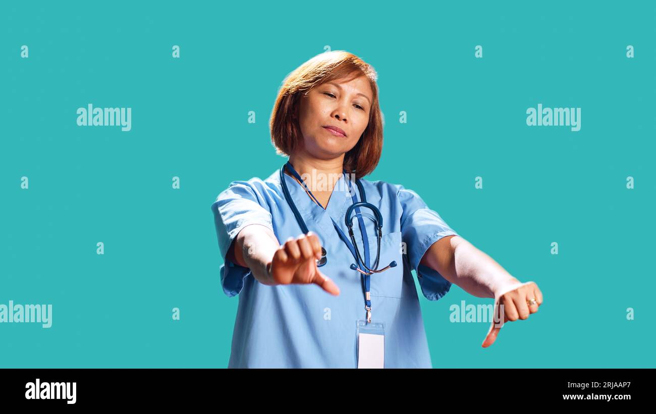Close up of upset hospital worker showing thumbs down signs while at ...