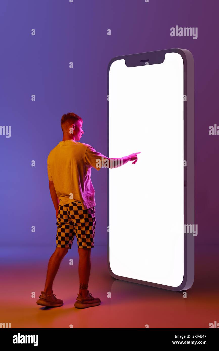 Young man scrolling giant 3d screen of mobile phone against gradient ...